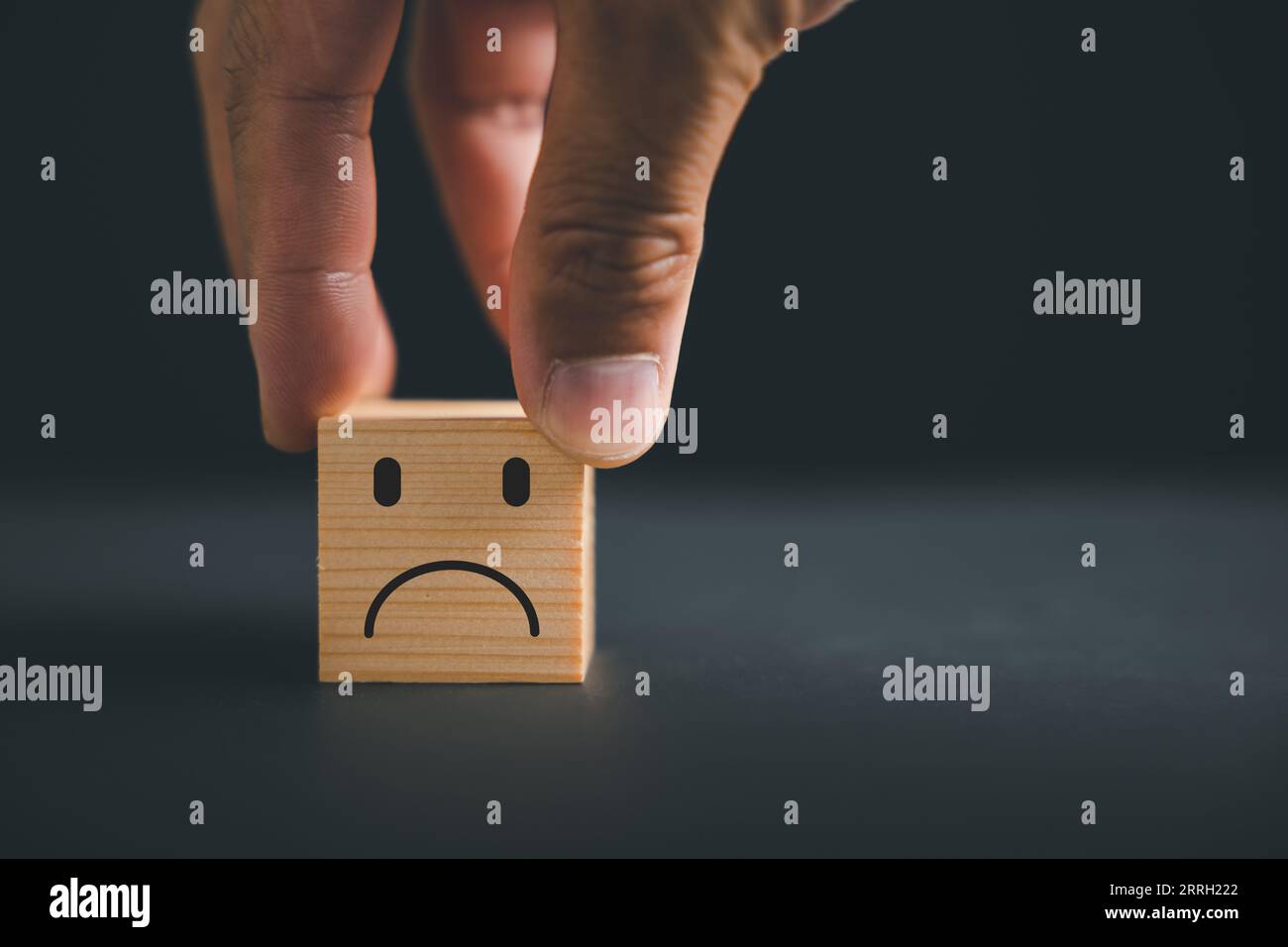 Unhappy customer hand with a sadness emotion face on a wooden block ...