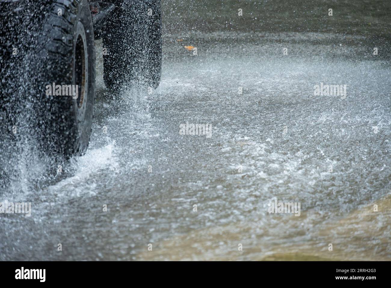 a car driving through the puddle and splashing water in a raining day ...