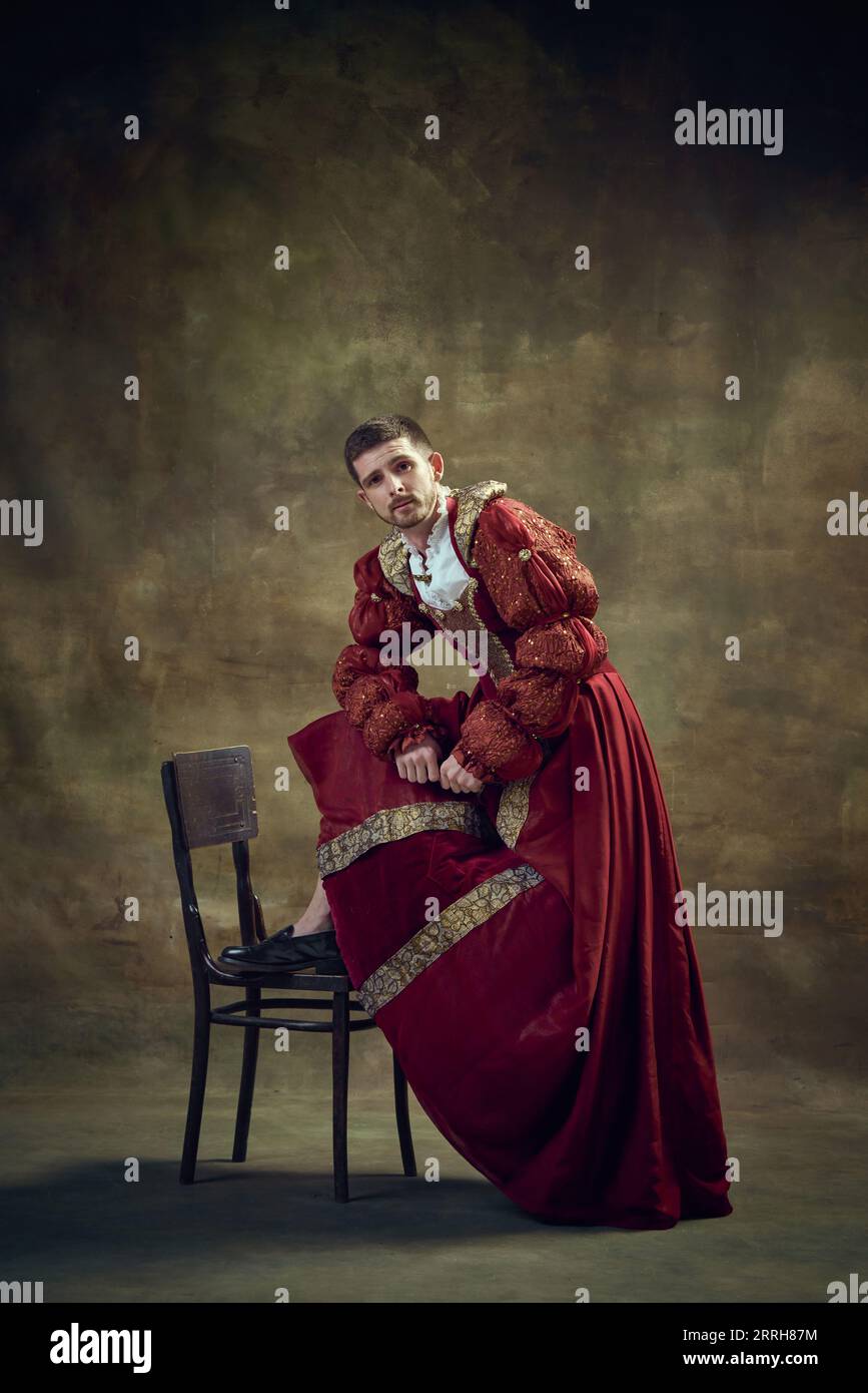 Young medieval prince, royal person leaning on chair, wearing female ...