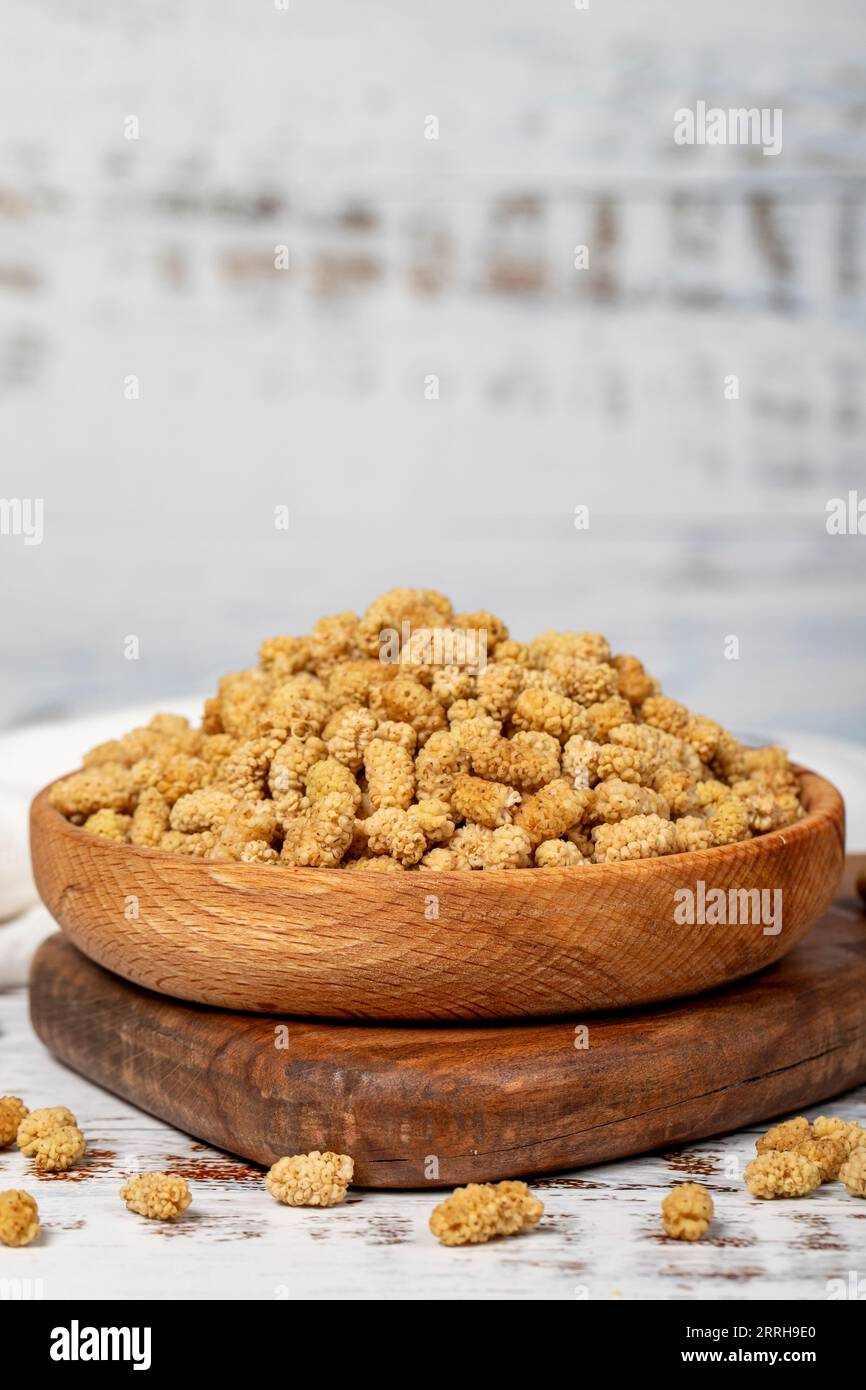 Dried mulberries in wooden bowl. Sun-dried mulberry on a white wood ...