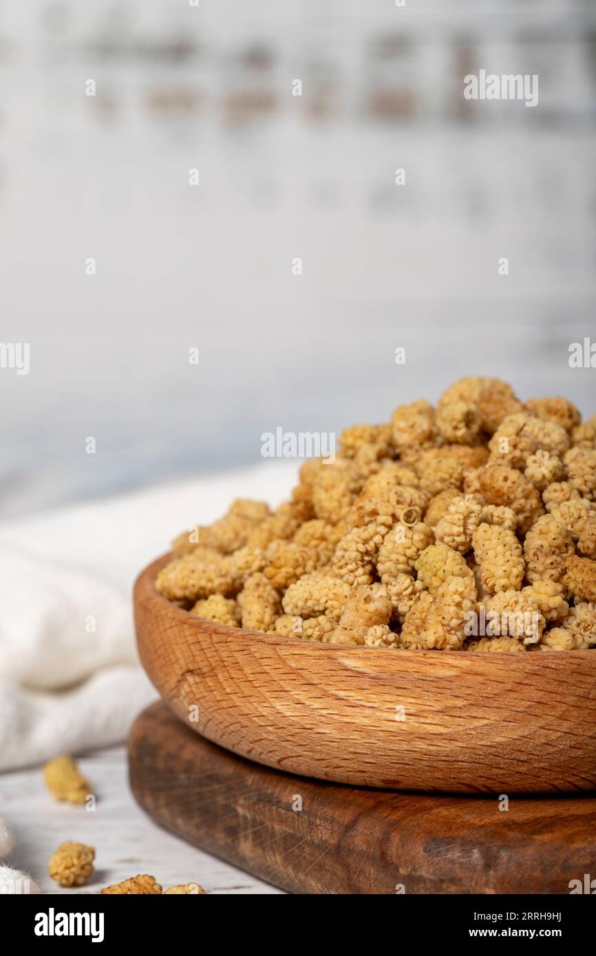 Dried mulberries in wooden bowl. Sun-dried mulberry on a white wood ...