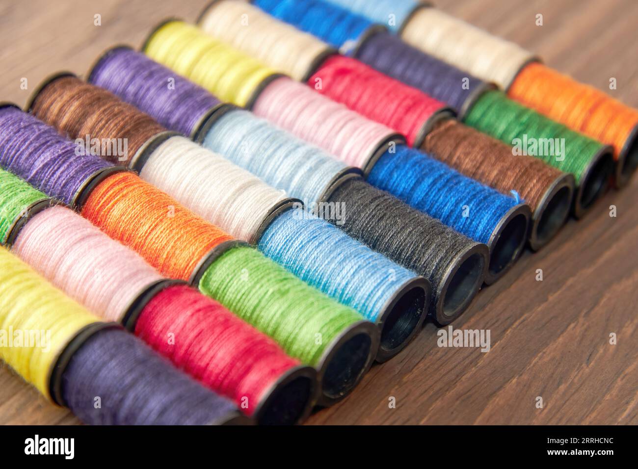 Set of colorful thread spools on the wooden seamstress's table. Sewing ...