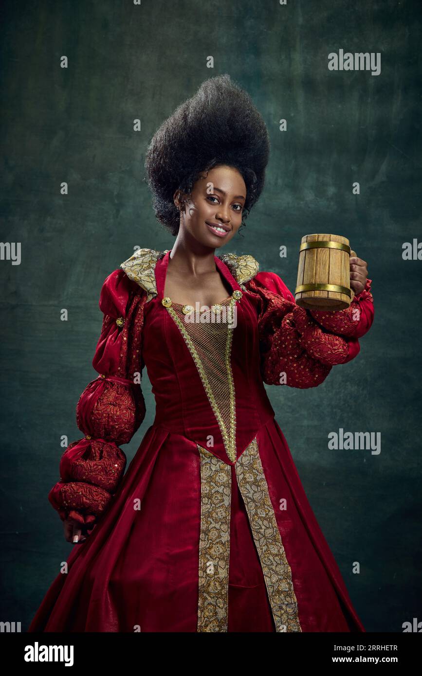 Positive, smiling young african woman, medieval queen in red dress ...