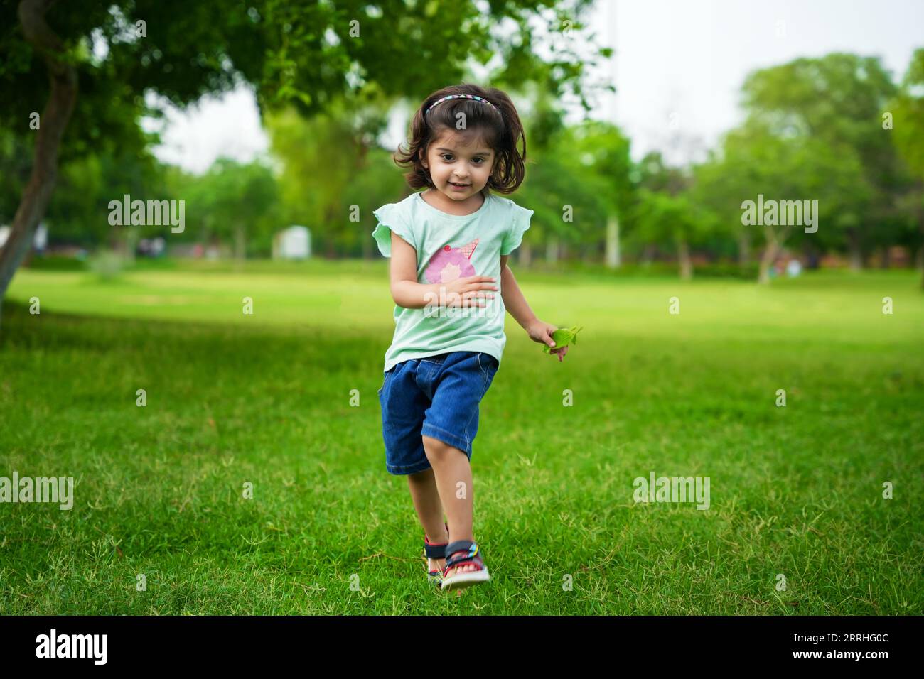 Cheerful and carefree little indian girl child running at summer park ...