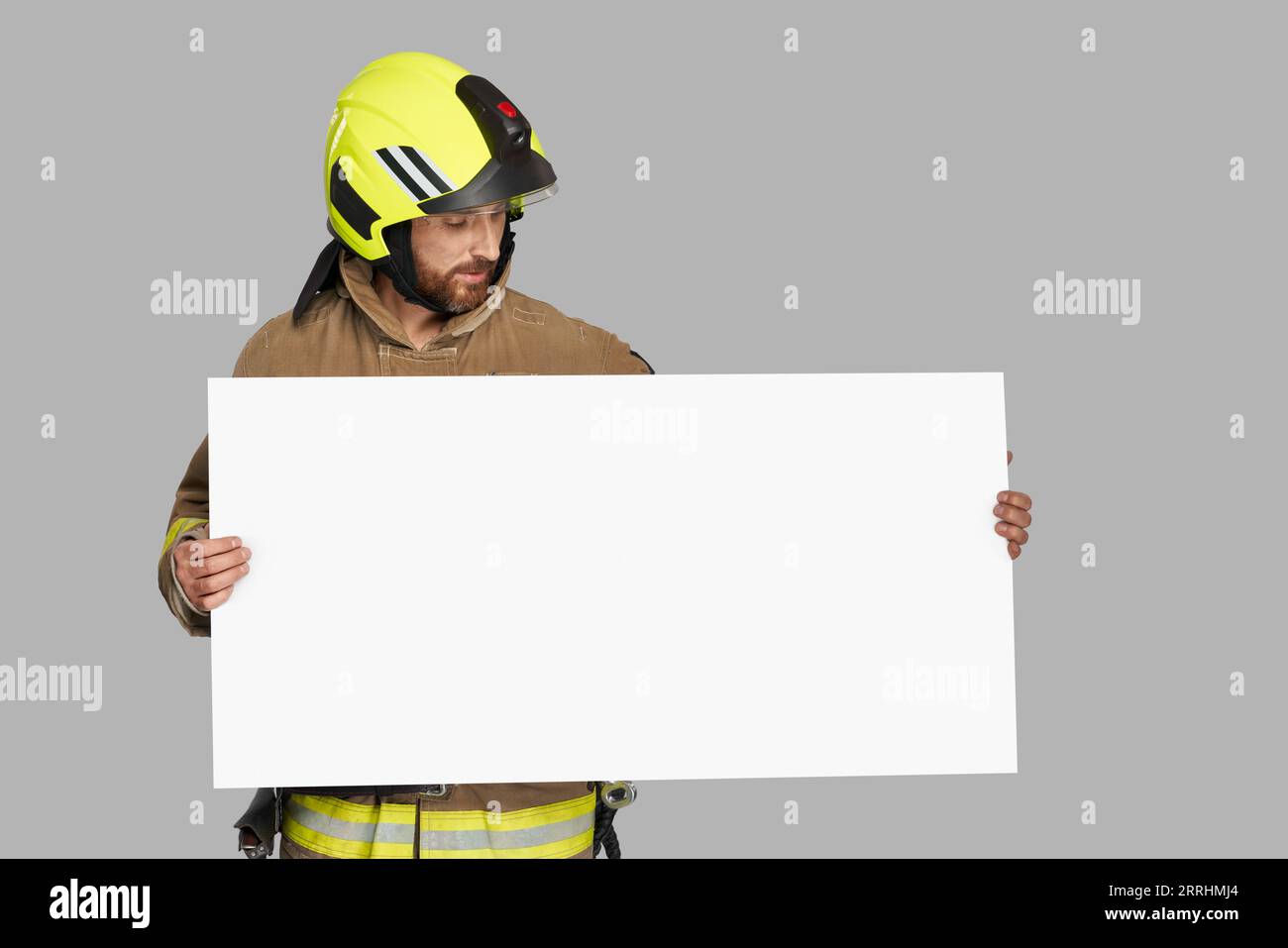Focused male firefighter looking at blank banner in front. Front view ...