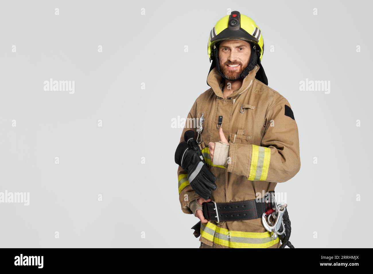 Happy caucasian firefighter in uniform showing thumb up in studio ...