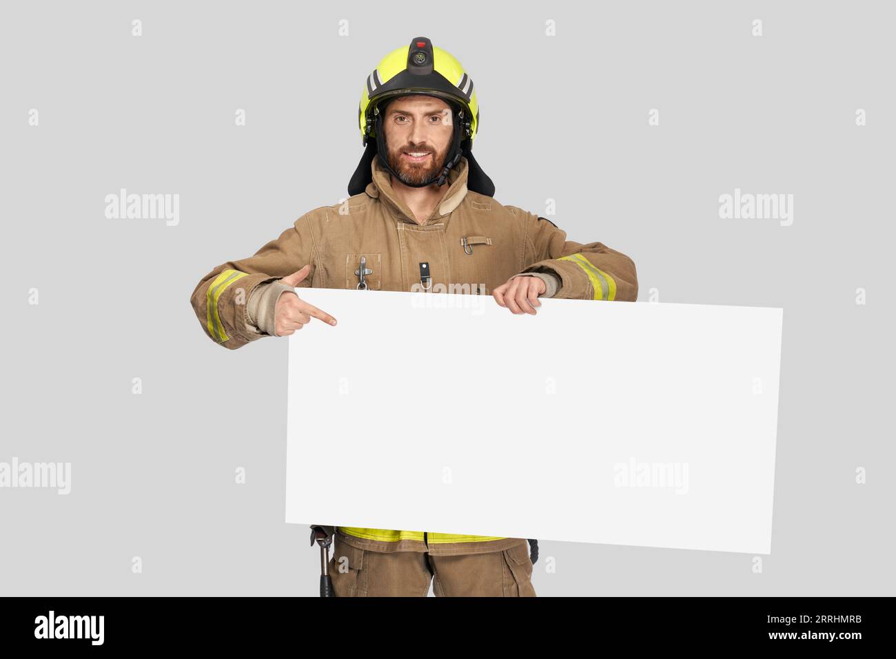 Smiling bearded firefighter pointing to empty banner in front. Front ...