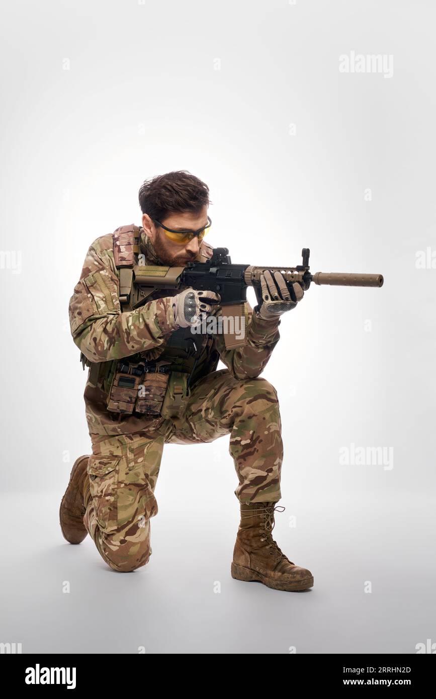 Focused special operations fighter aiming from assault rifle indoors ...