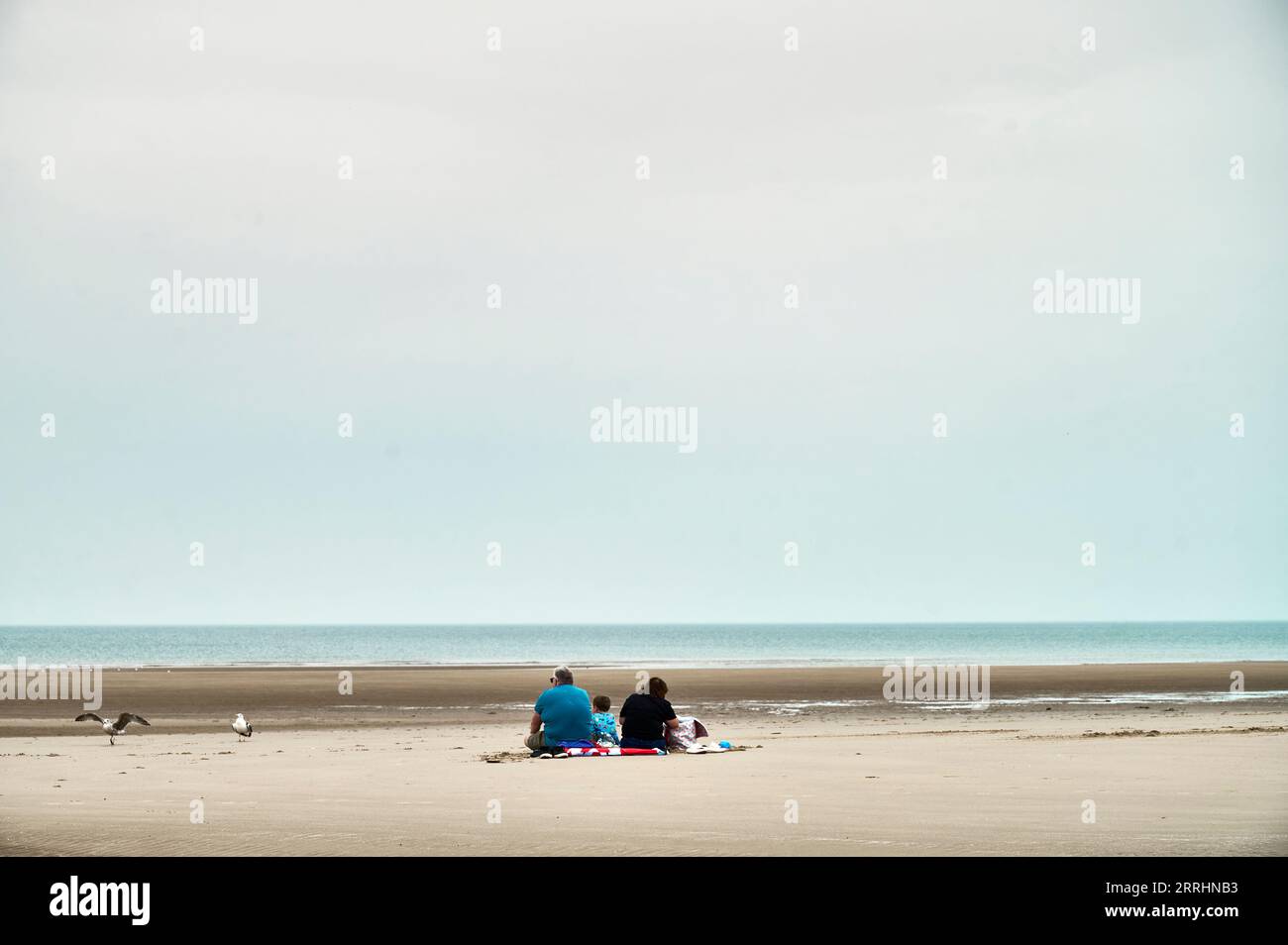 Family of three on an oterwise empty Blackpool beach at the end of ...