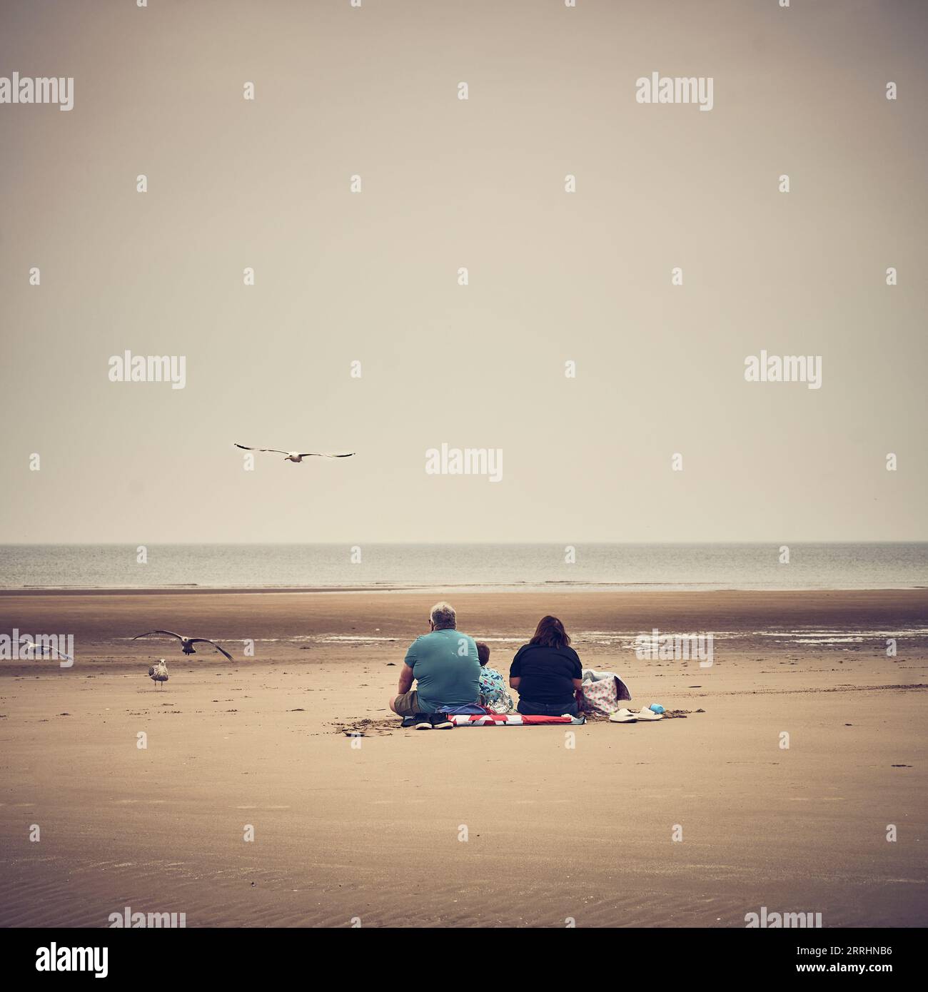 Family of three on an oterwise empty Blackpool beach at the end of ...
