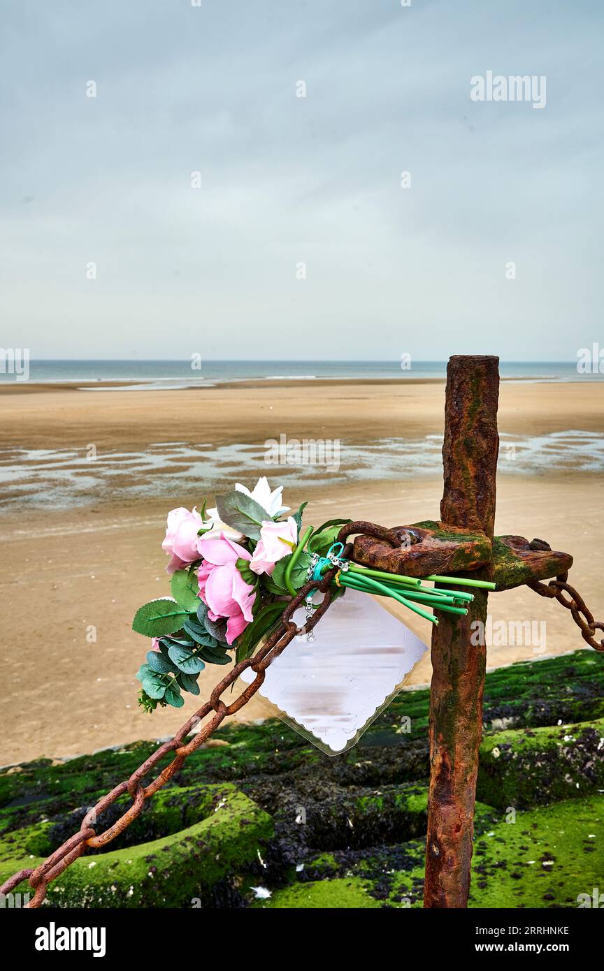 Plastic memorial flowers attached to chain on seawall fence Stock Photo ...