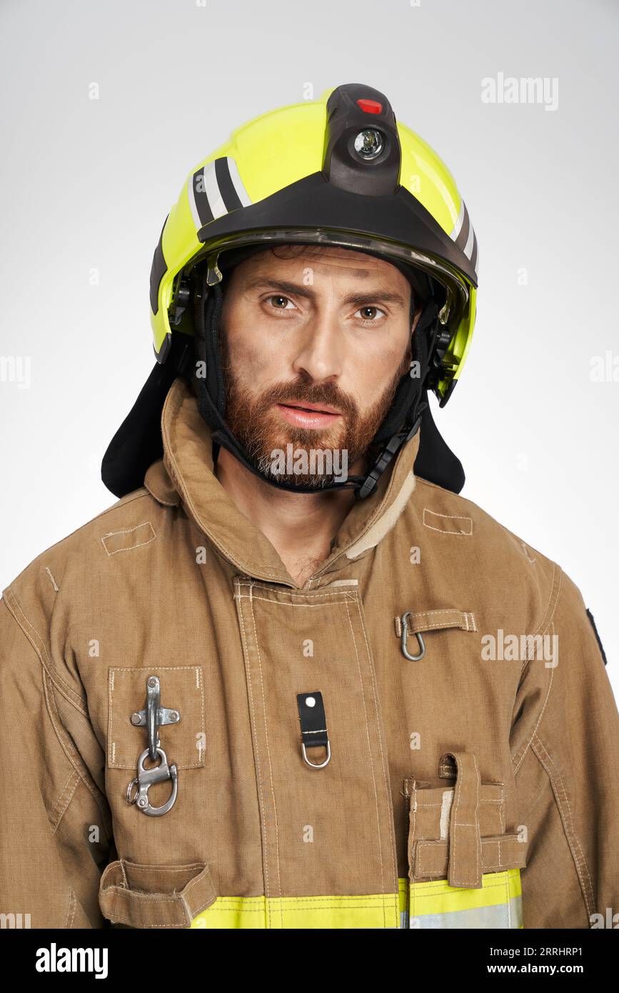 Exhausted caucasian firefighter in helmet tiredly looking at camera ...