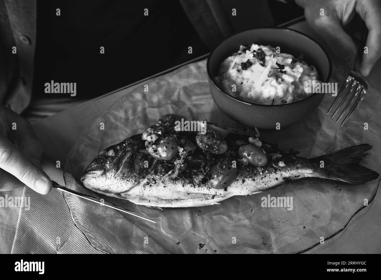 Man eating grilled dorada fish and rice with celery root puree in a ...
