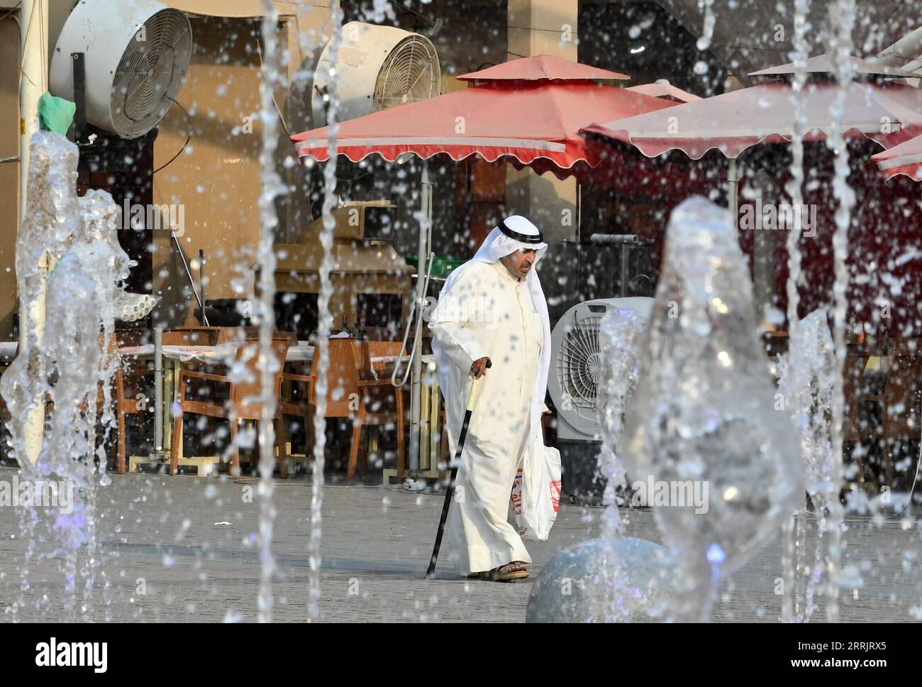 220807 -- KUWAIT CITY, Aug. 7, 2022 -- A man walks past a splash pad ...