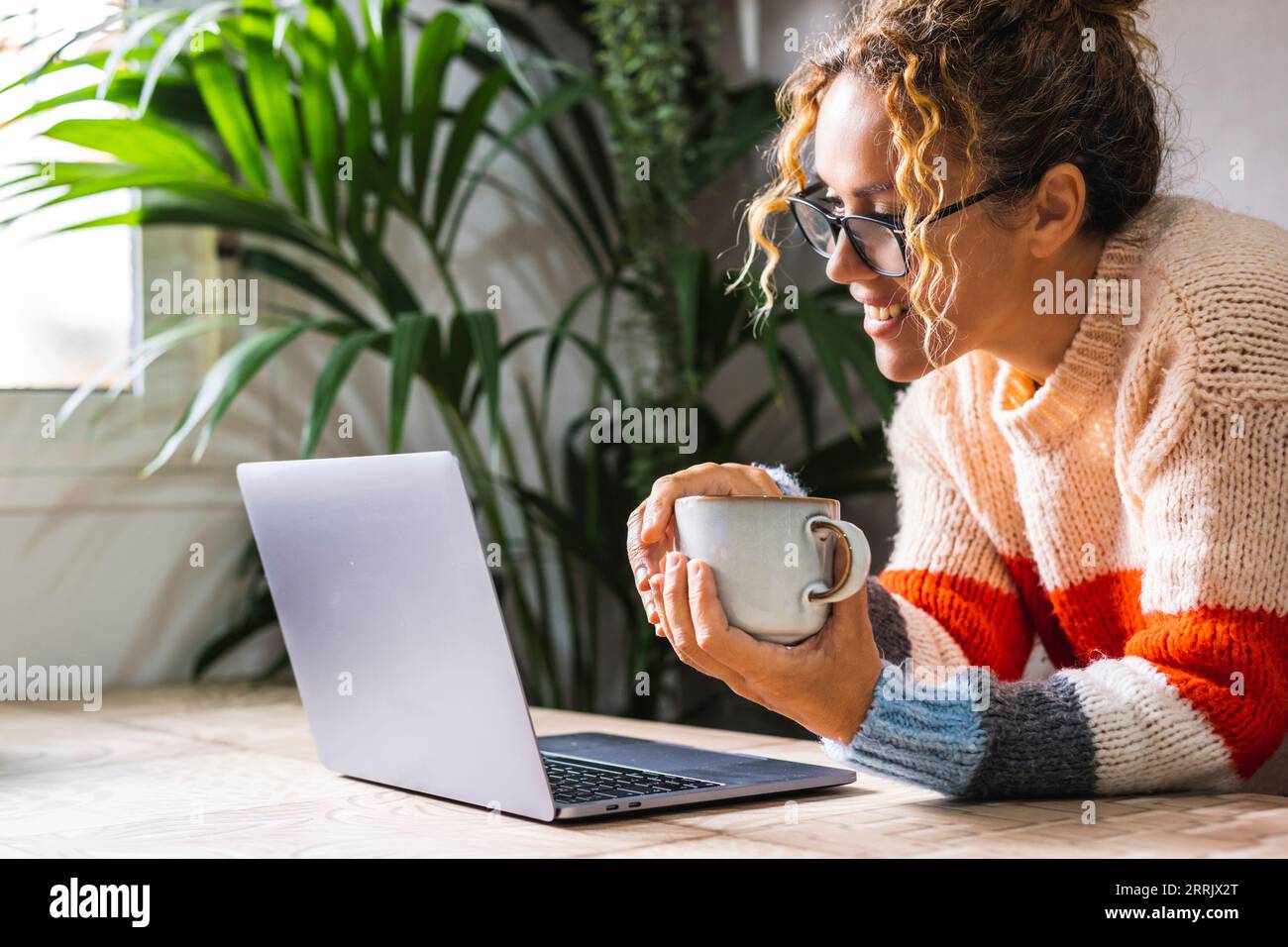 Modern cute woman smiling at the laptop display and enjoying time ...