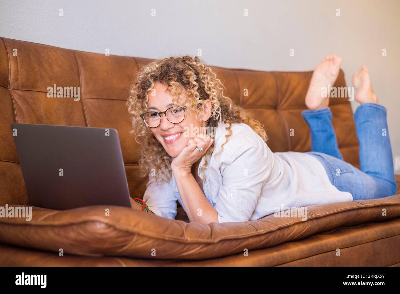 Smiling woman at home watching laptop screen. Portrait of cheerful ...
