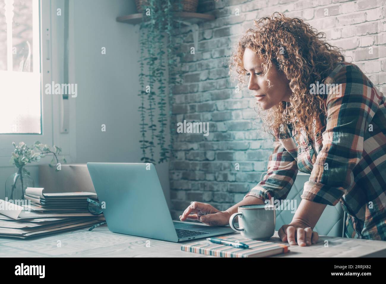 Modern woman at home using laptop on the table with wireless internet ...