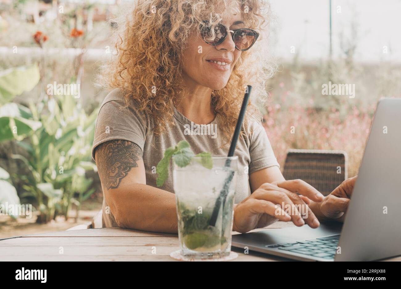 Modern female freelance adult working on laptop sitting outdoor at the ...