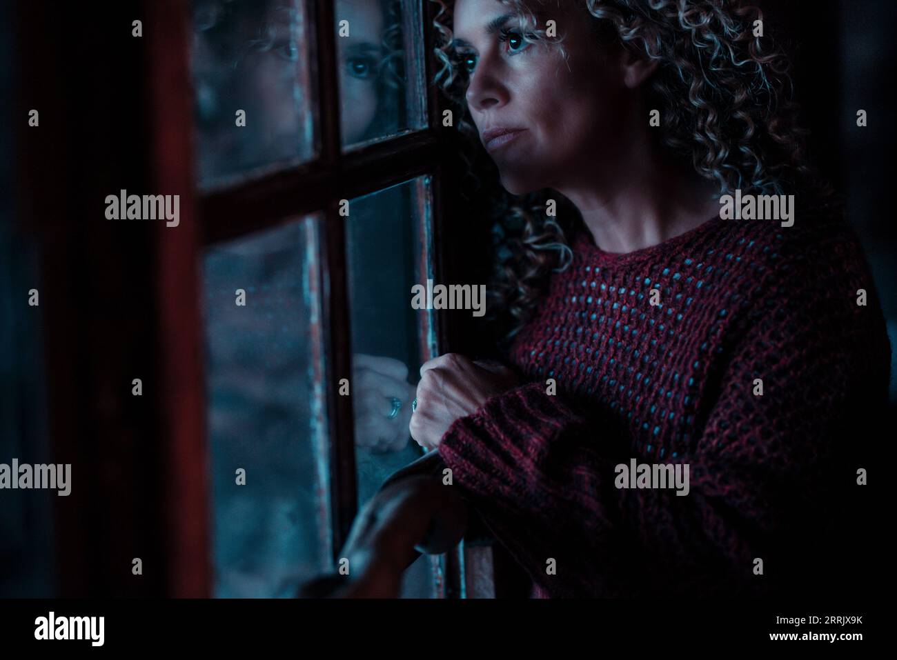 Portrait of woman indoor at home in the dark looking outside the window ... Portrait of woman indoor at home in the dark looking outside the window ...