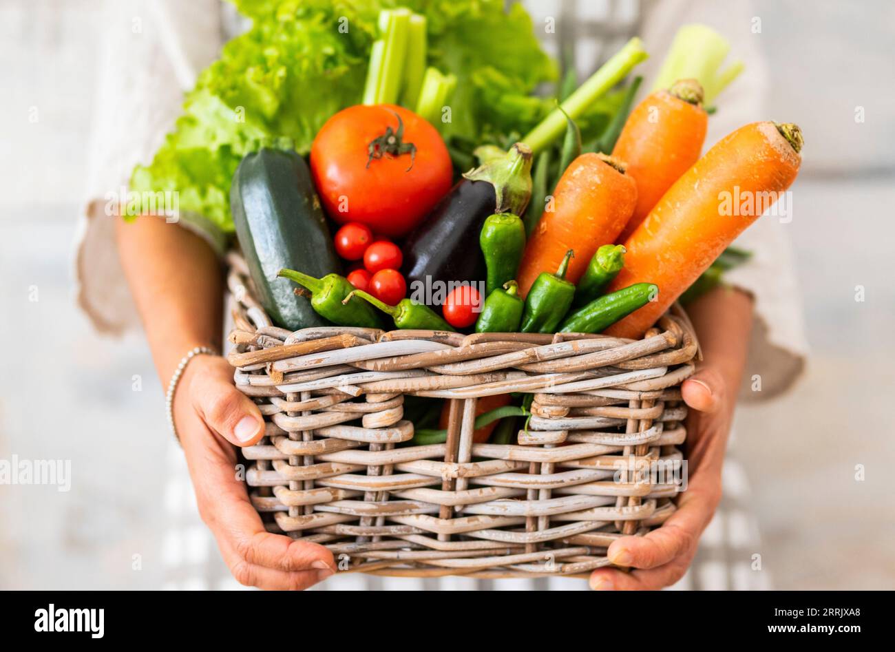 Unrecognizable vegetable store owner holding basket full of colorful ...