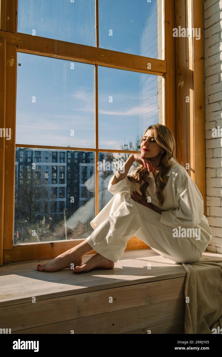 beautiful woman near window highlighted with bright sun Stock Photo - Alamy