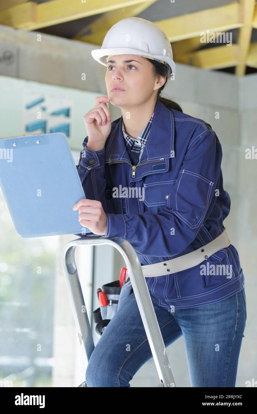portrait of female worker thinking up in a ladder Stock Photo - Alamy