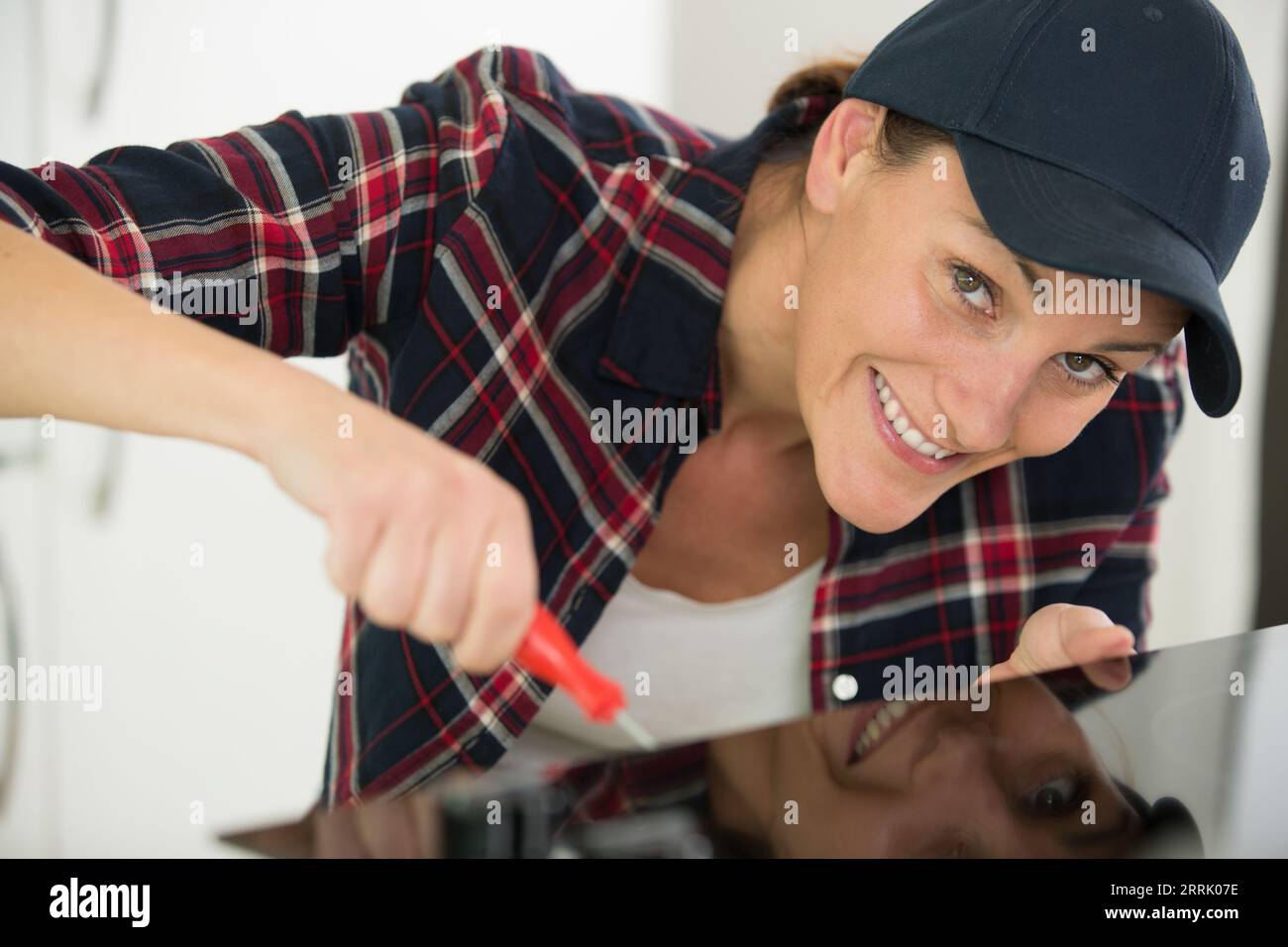 happy woman builder using a screwdriver Stock Photo - Alamy