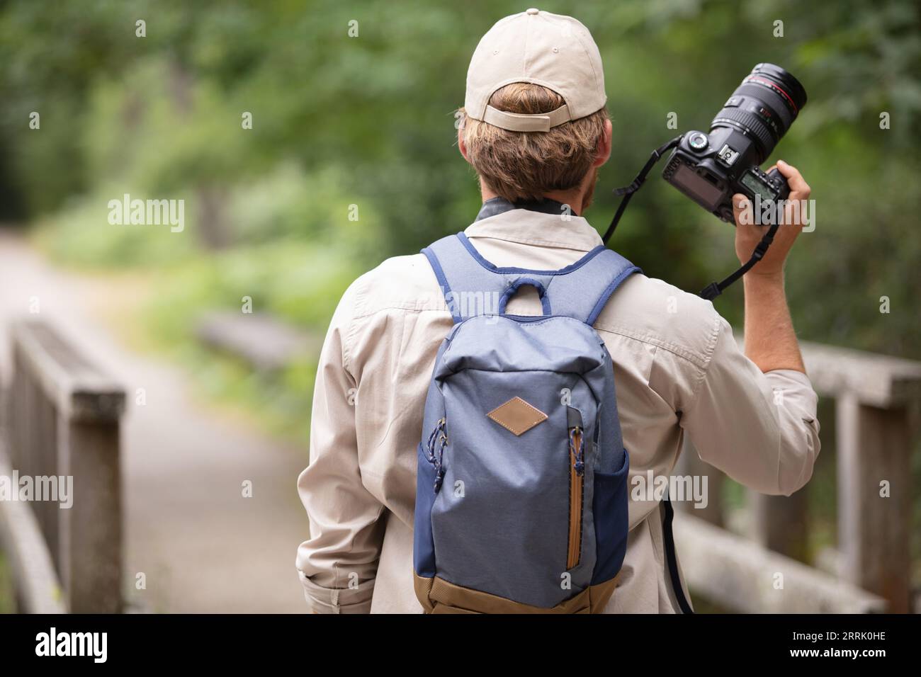 rear view of man wearing rucksack and holding camera Stock Photo - Alamy