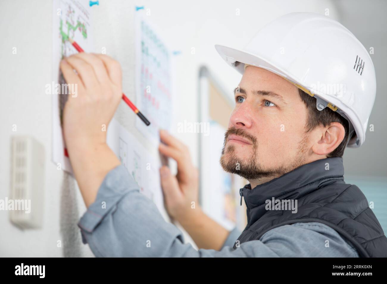 man wearing safety-helmet writing information on noticeboard Stock ...