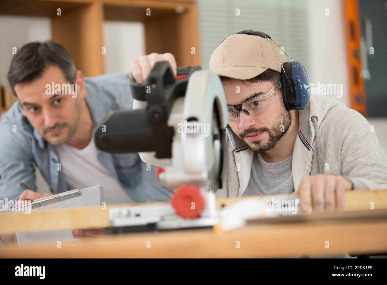 supervisor assessing student using a circular saw Stock Photo - Alamy