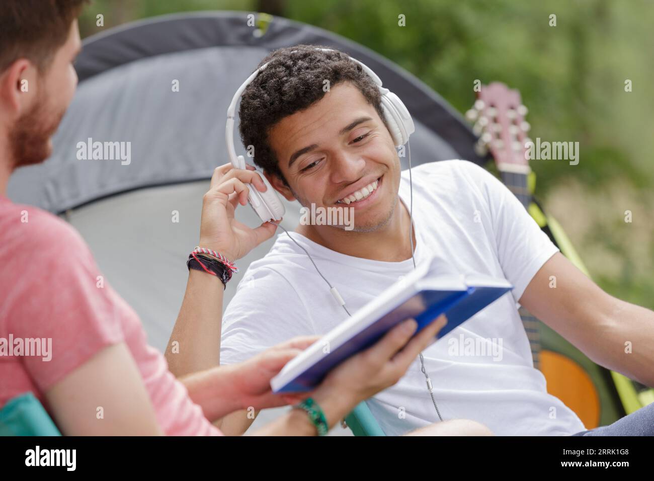 camping man reading a book with friend Stock Photo - Alamy