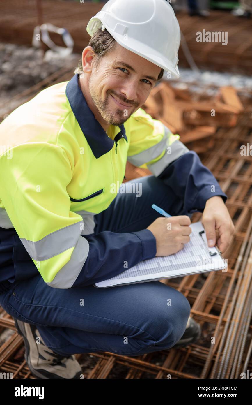 worker with clipboard crouching on stack of rebars Stock Photo - Alamy