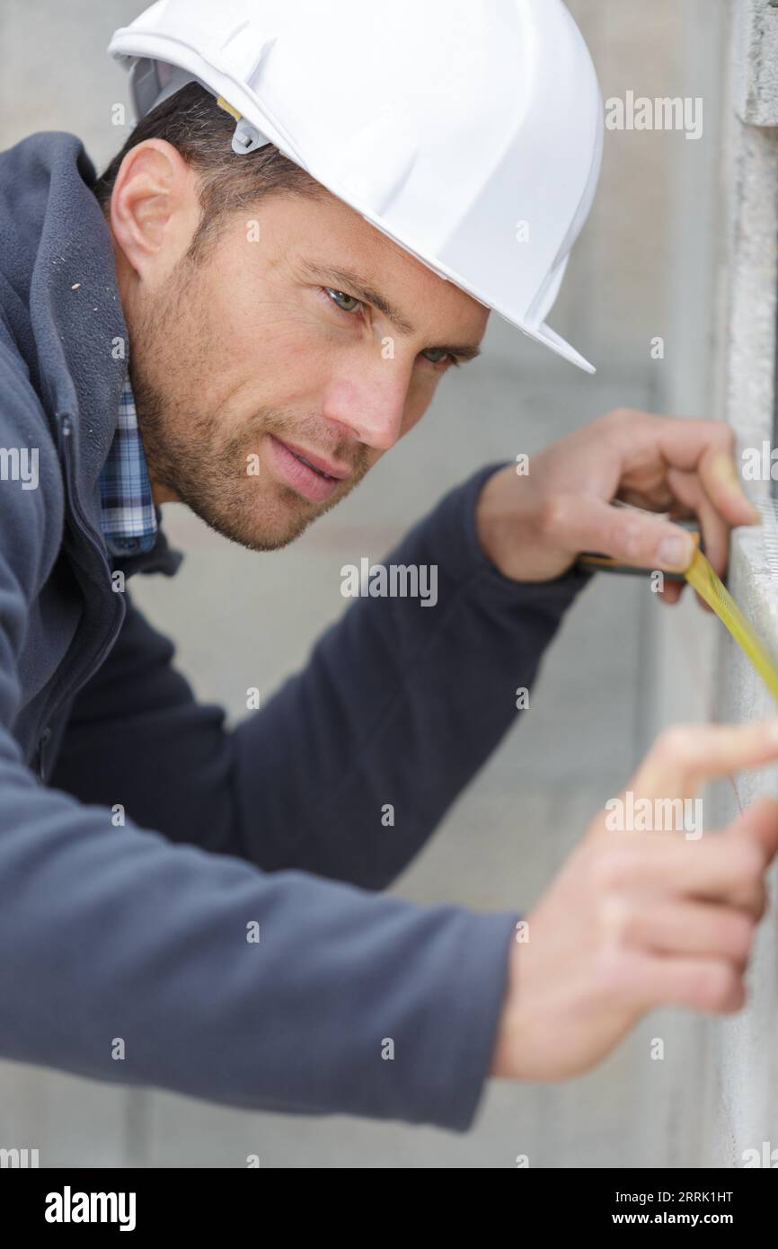man measuring half constructed wall with tape measure Stock Photo - Alamy