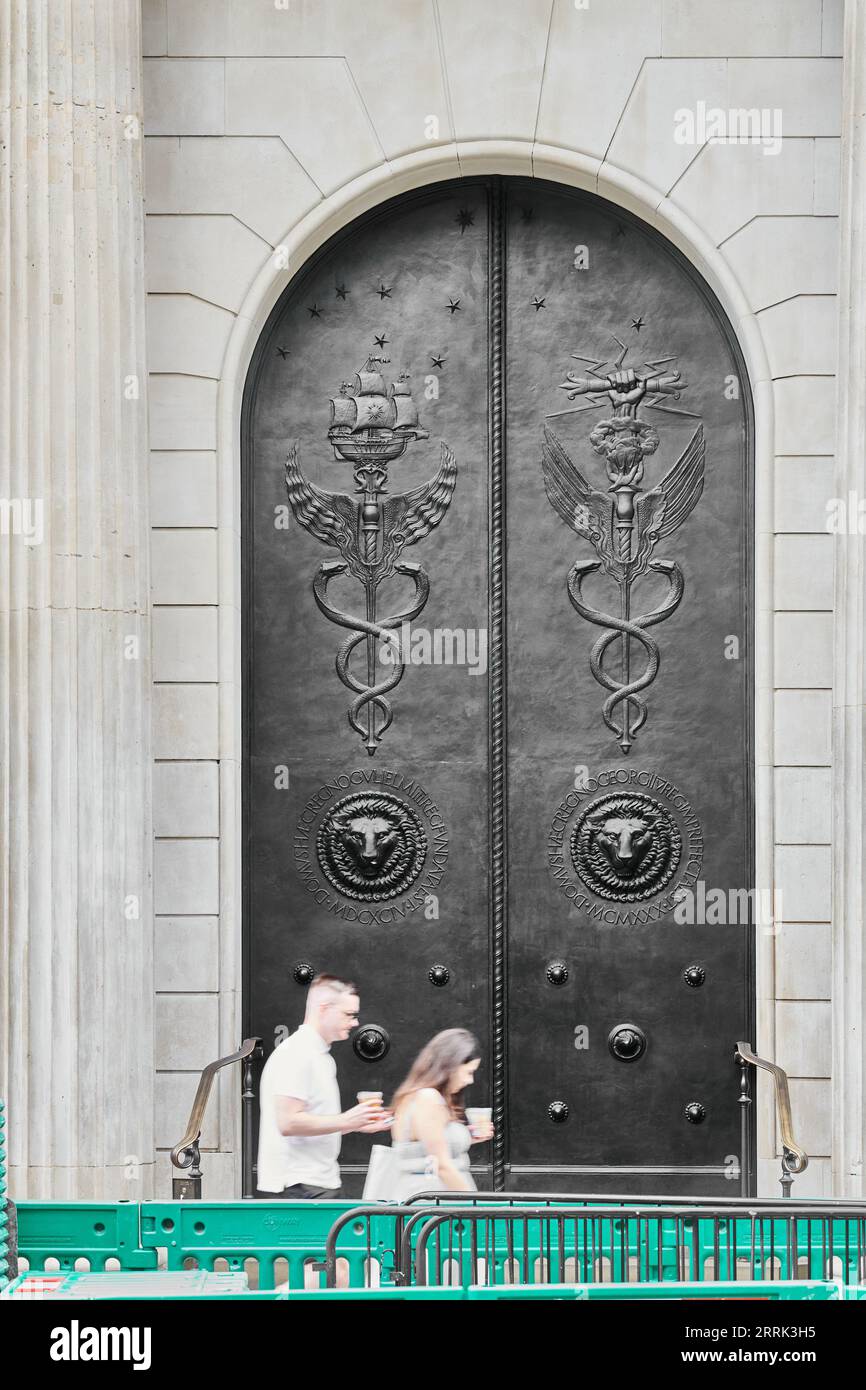 A couple walk pasts a door to the Bank of England, Threadneedle Street ...