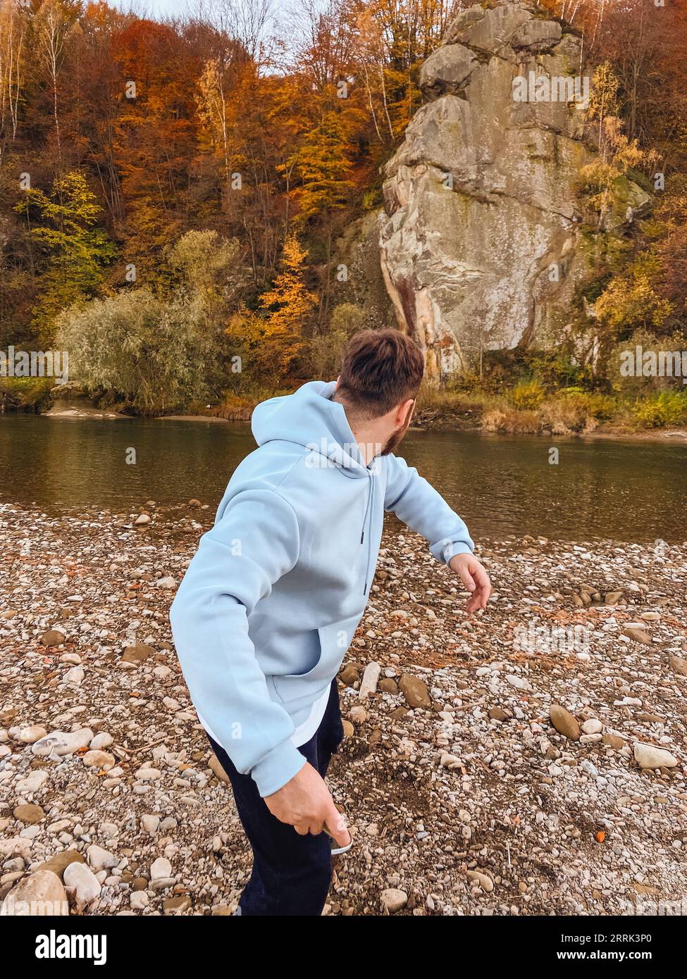 man throwing rocks into river autumn season Stock Photo - Alamy
