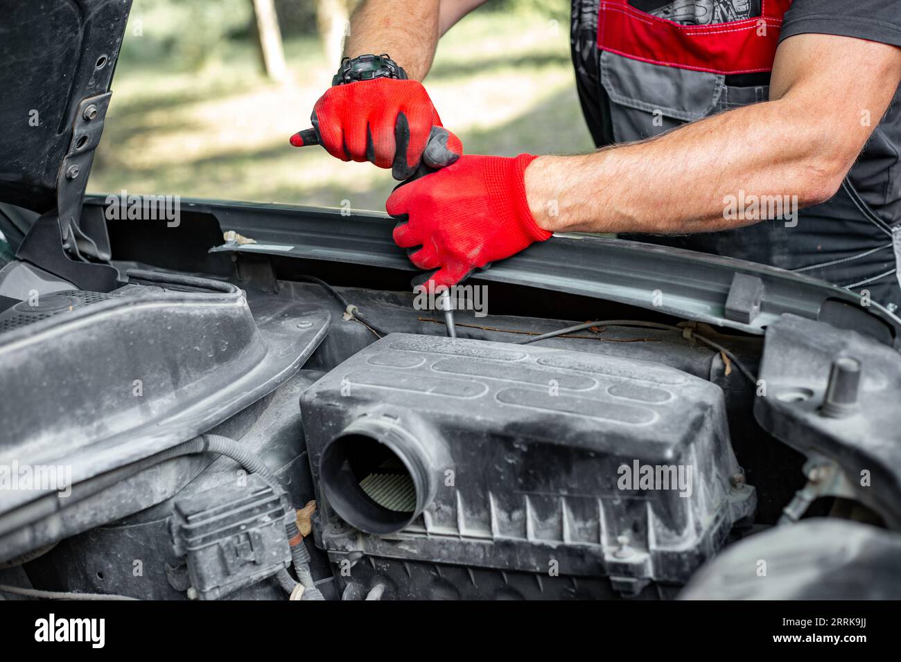 Car repair. An auto mechanic opens the air filter housing of an ...