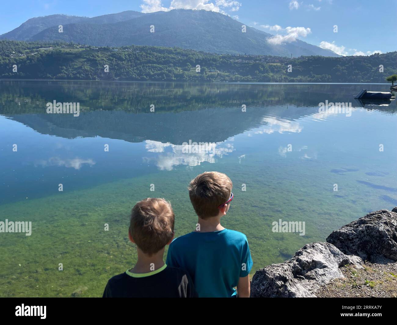Two boys looking at the calm lake caldonazzo in trentino hi-res stock ...