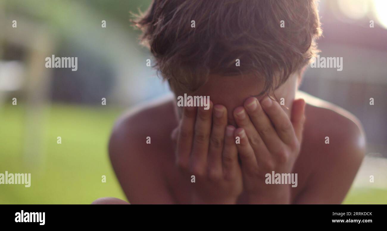 Boy covering face with hands feeling sad, child peeking from hands ...