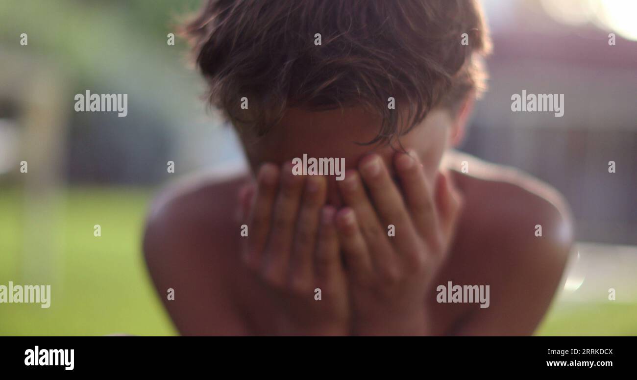Boy covering face with hands feeling sad, child peeking from hands ...
