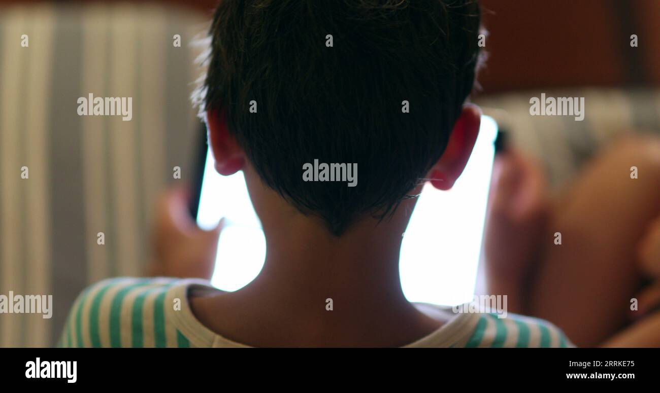 Back of child head staring at screen device at night Stock Photo - Alamy