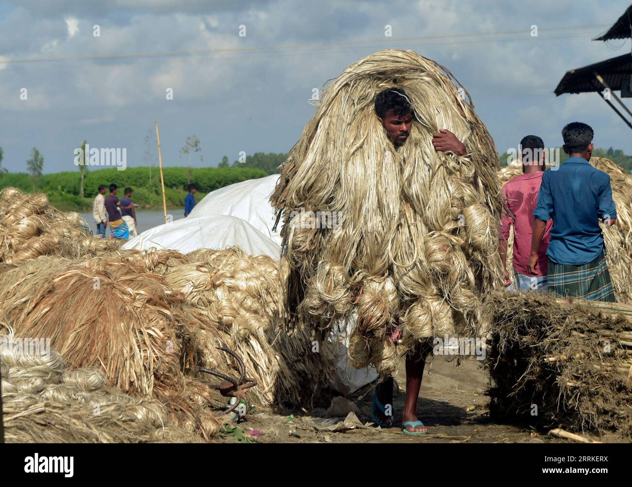 220905 -- MUNSHIGANJ, Sept. 5, 2022 -- A laborer carries bundles of ...