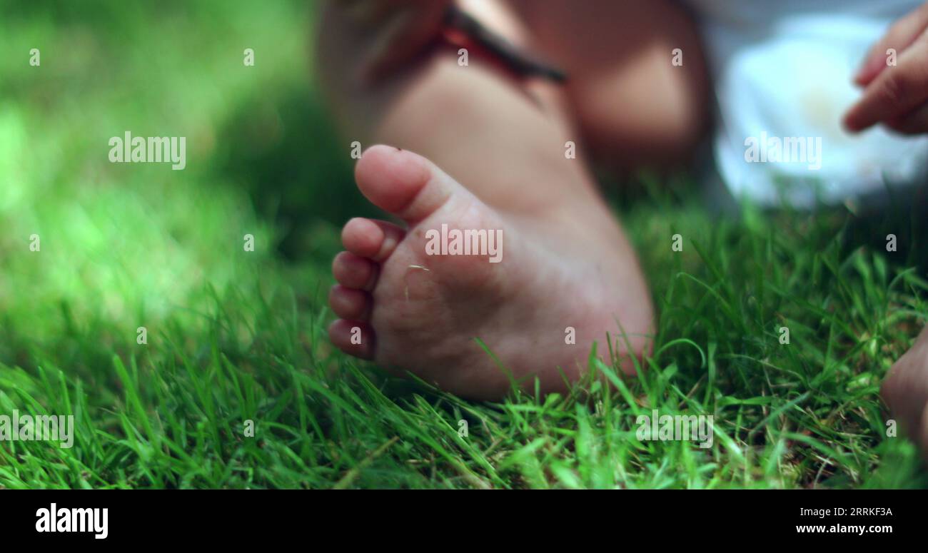 Baby infant toes and feet on grass outside in nature. Toddler legs ...