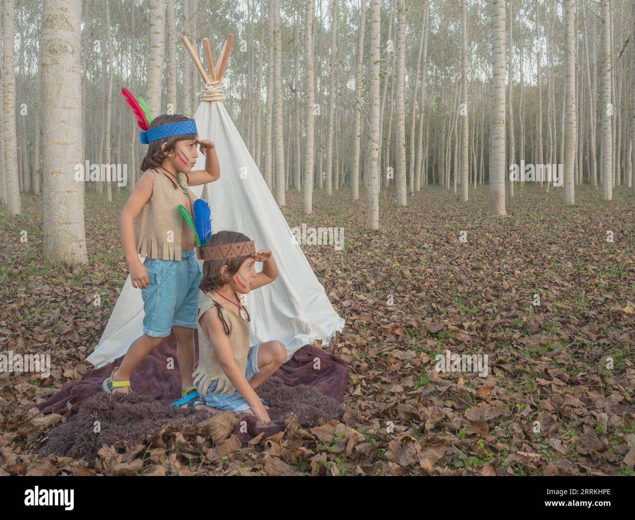 Twins playing at being Native Americans next to a tepee and with their ...