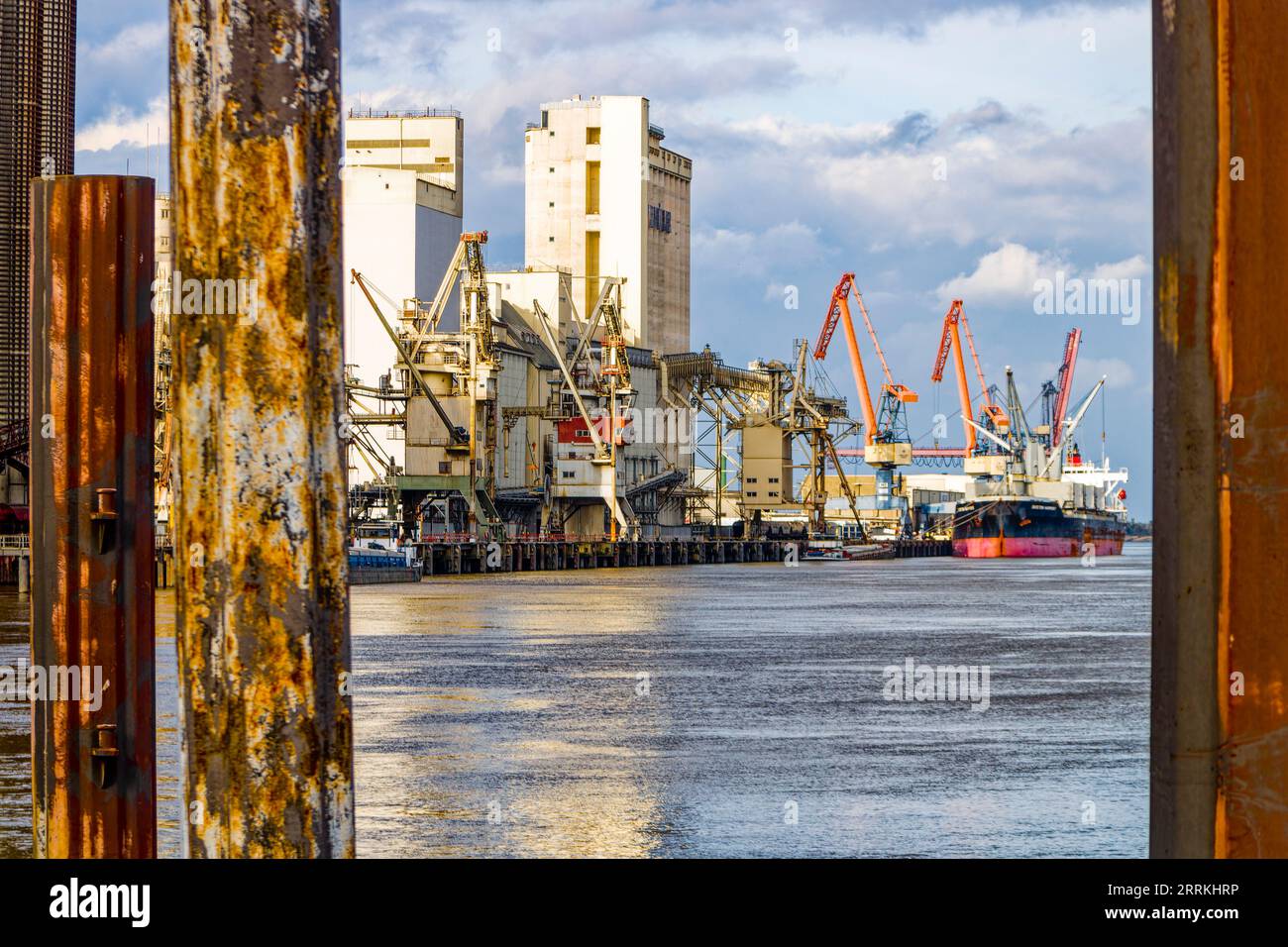 Port facilities with cargo cranes, warehouse buildings and cargo ship ...