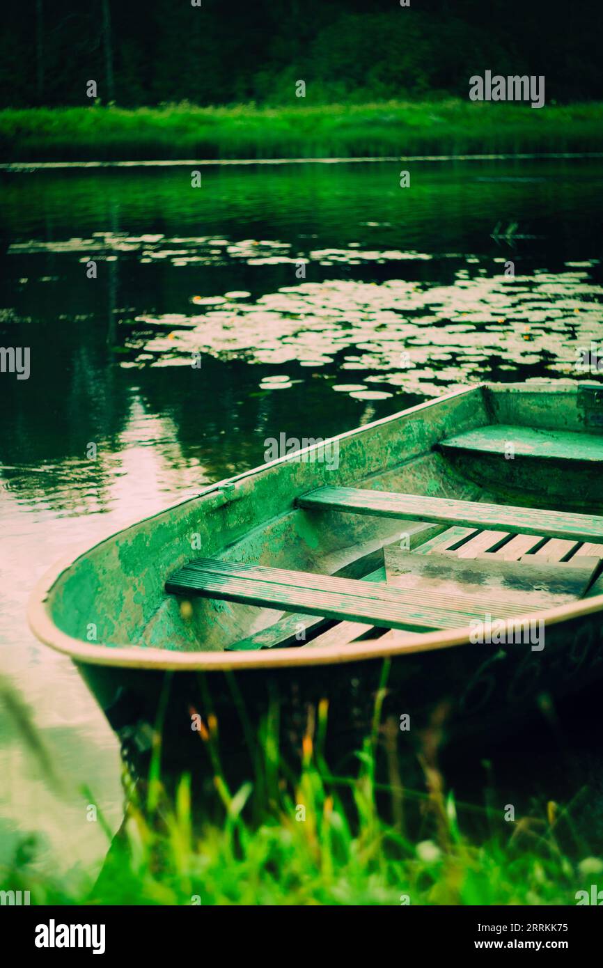 A beautiful old fishing boat is floating along a grassy riverbank on a ...