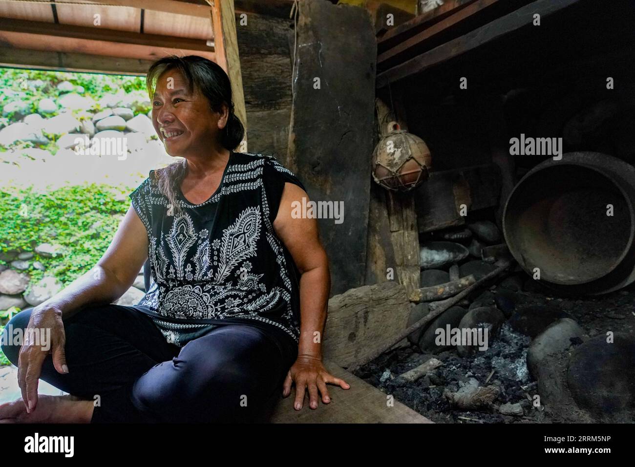 Ayoy, a mid-aged aboriginal from Tao community, is talking with a tourist near the kitchen stove ...