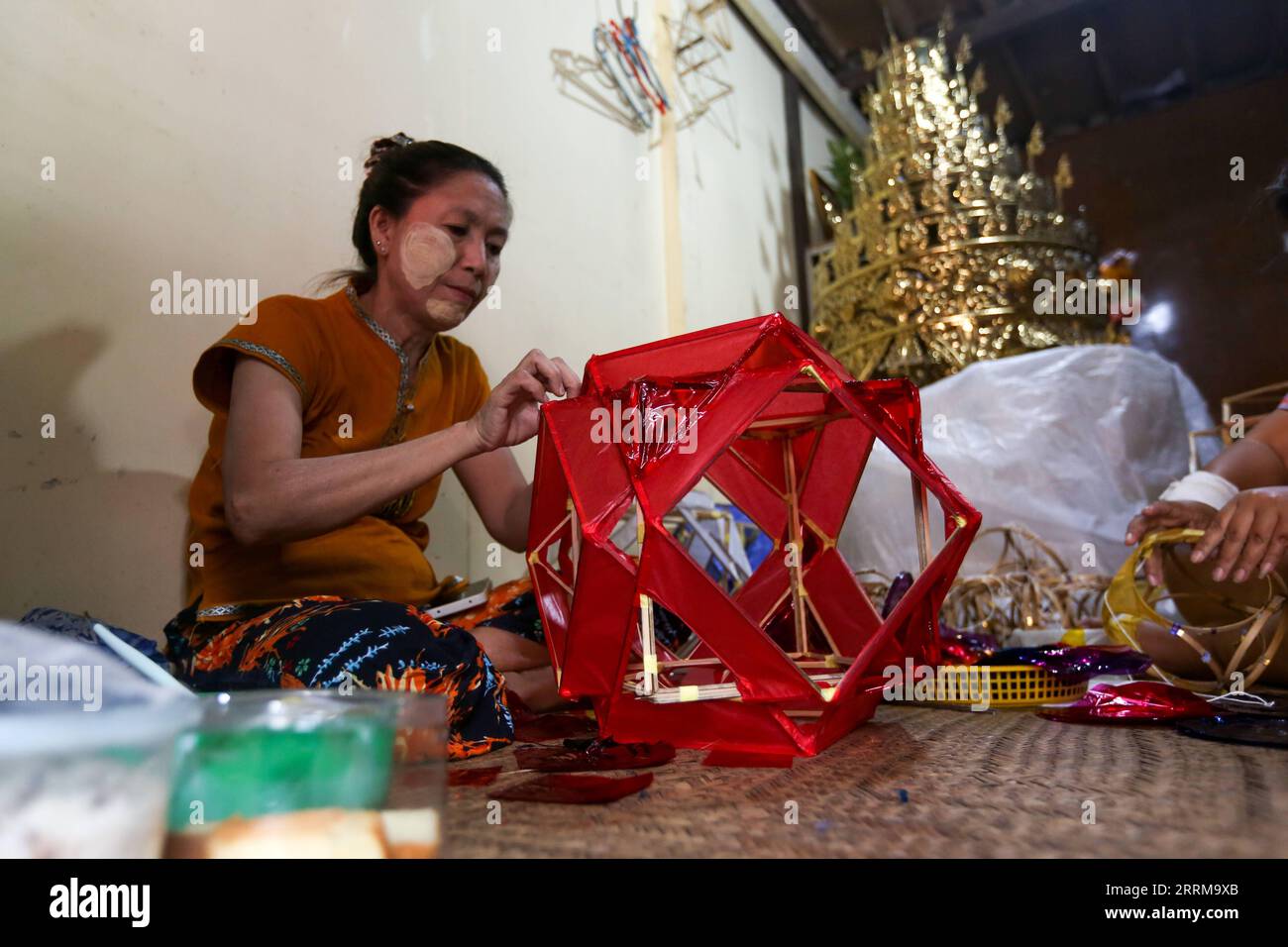 221009 -- YANGON, Oct. 9, 2022 -- A woman makes a traditional lantern ...