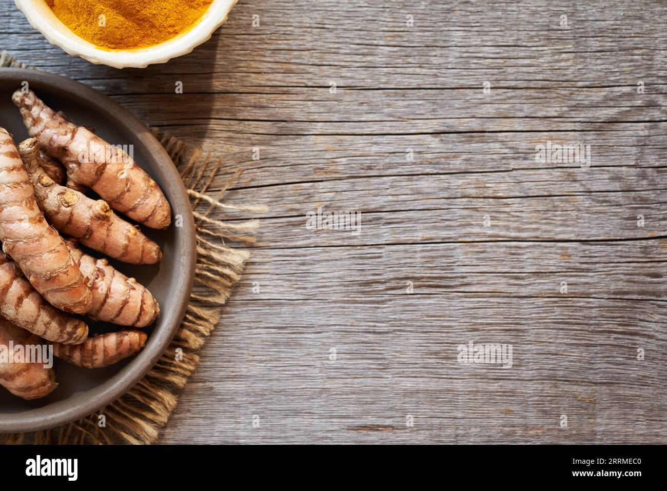 Fresh turmeric root and dried curcuma powder on a wooden rustic ...