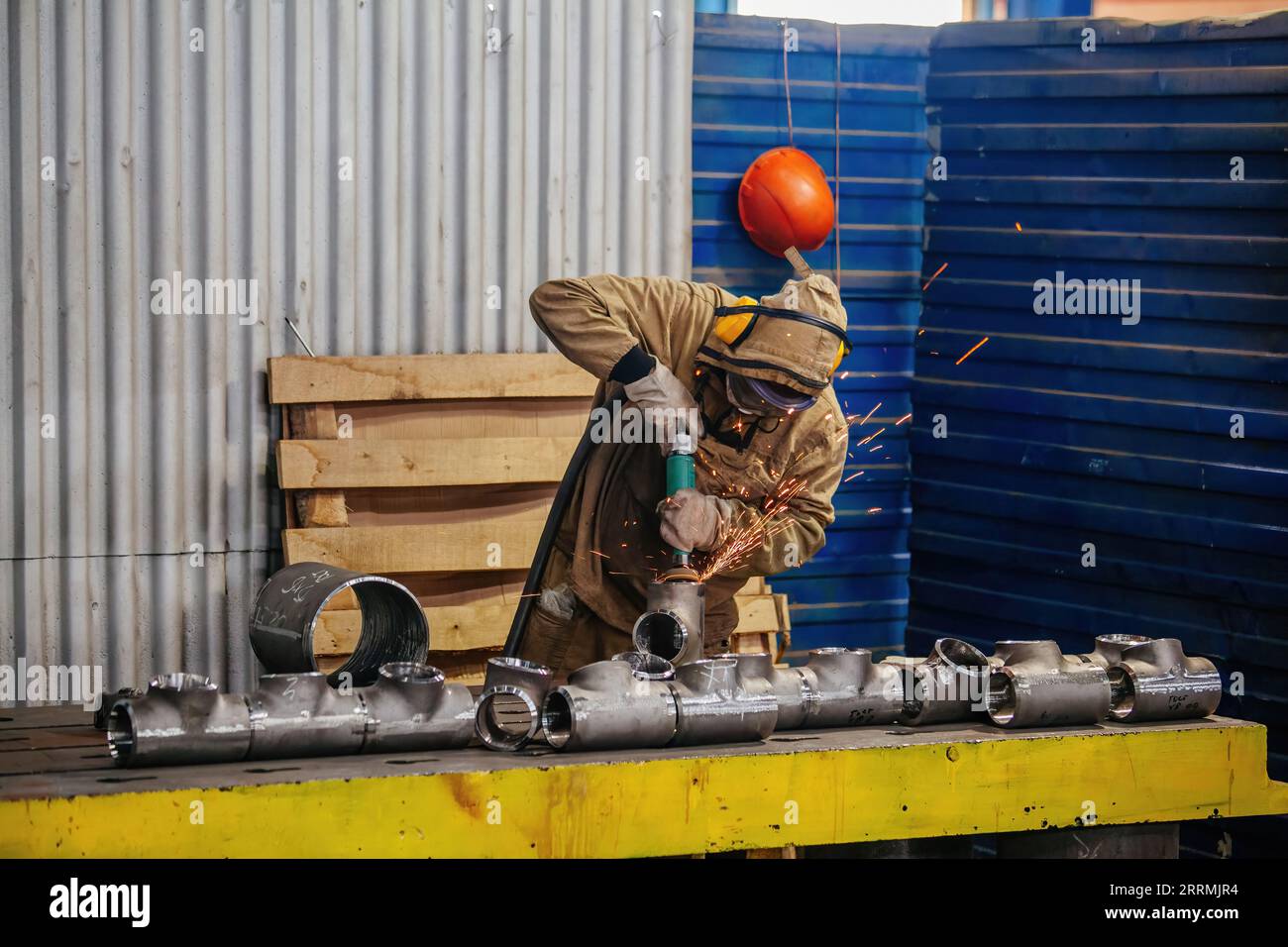 Male worker grinding T shape pipe parts in factory Stock Photo - Alamy