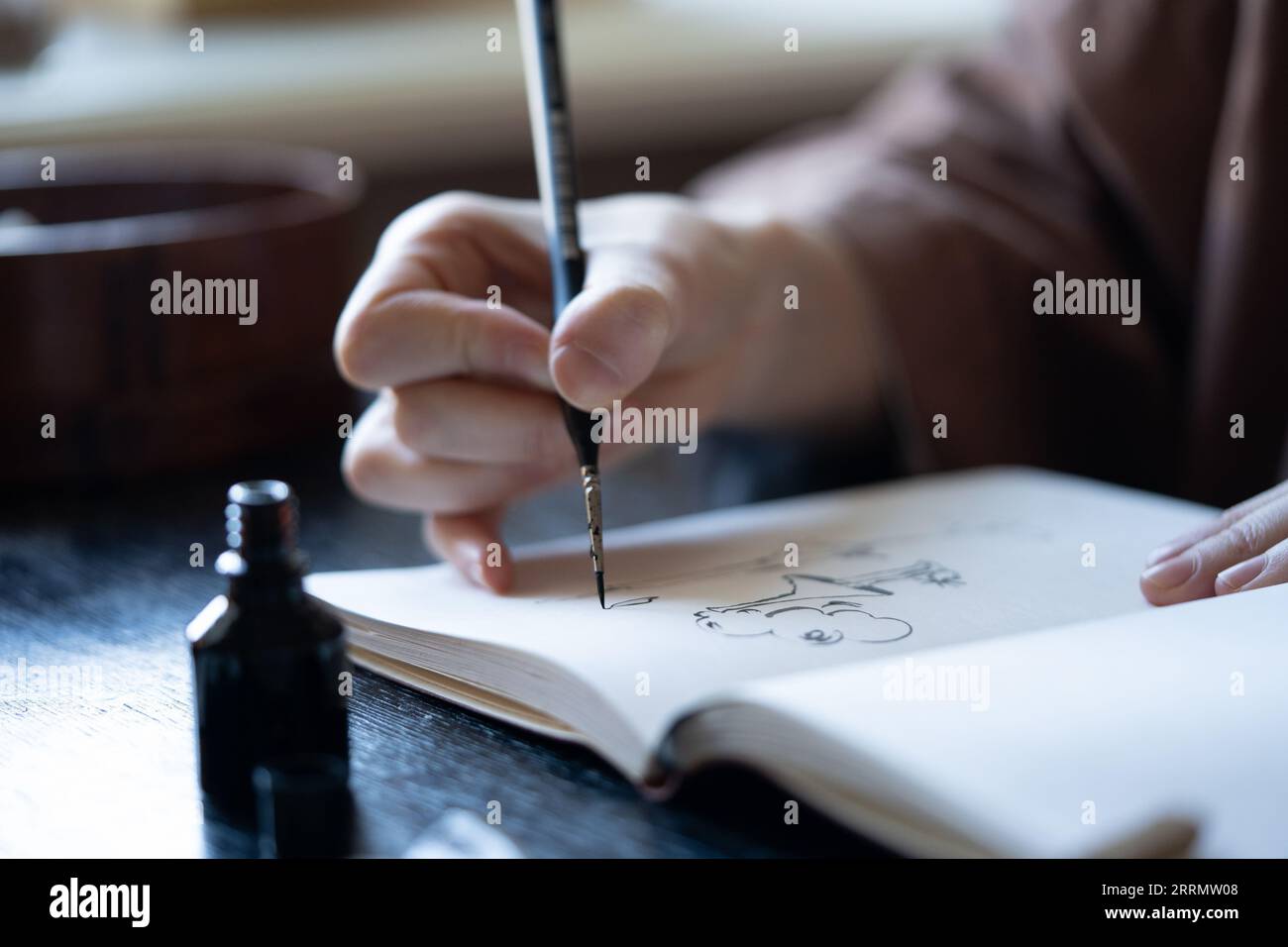 Illustrator freelancer holds fountain pen make sketch in notebook for ...